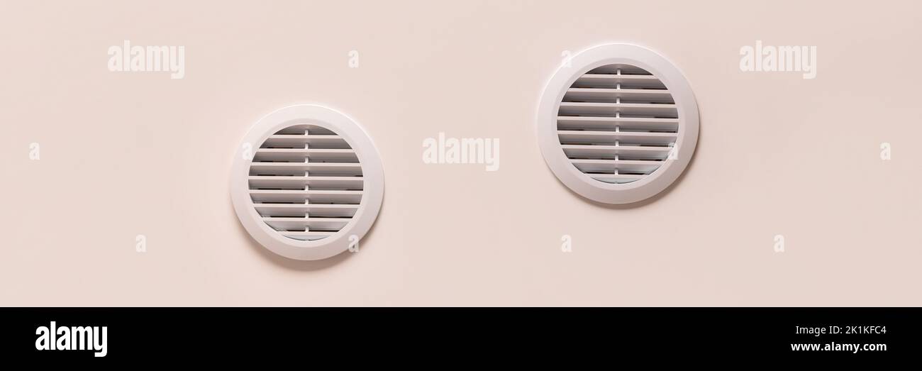 Round air vents with white plastic grate on beige ceiling with copy ...