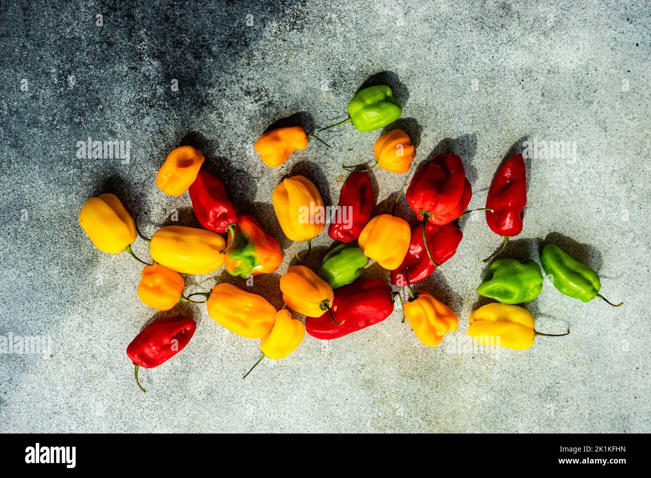 Overhead view of assorted red, green and yellow chilli peppers on a ...