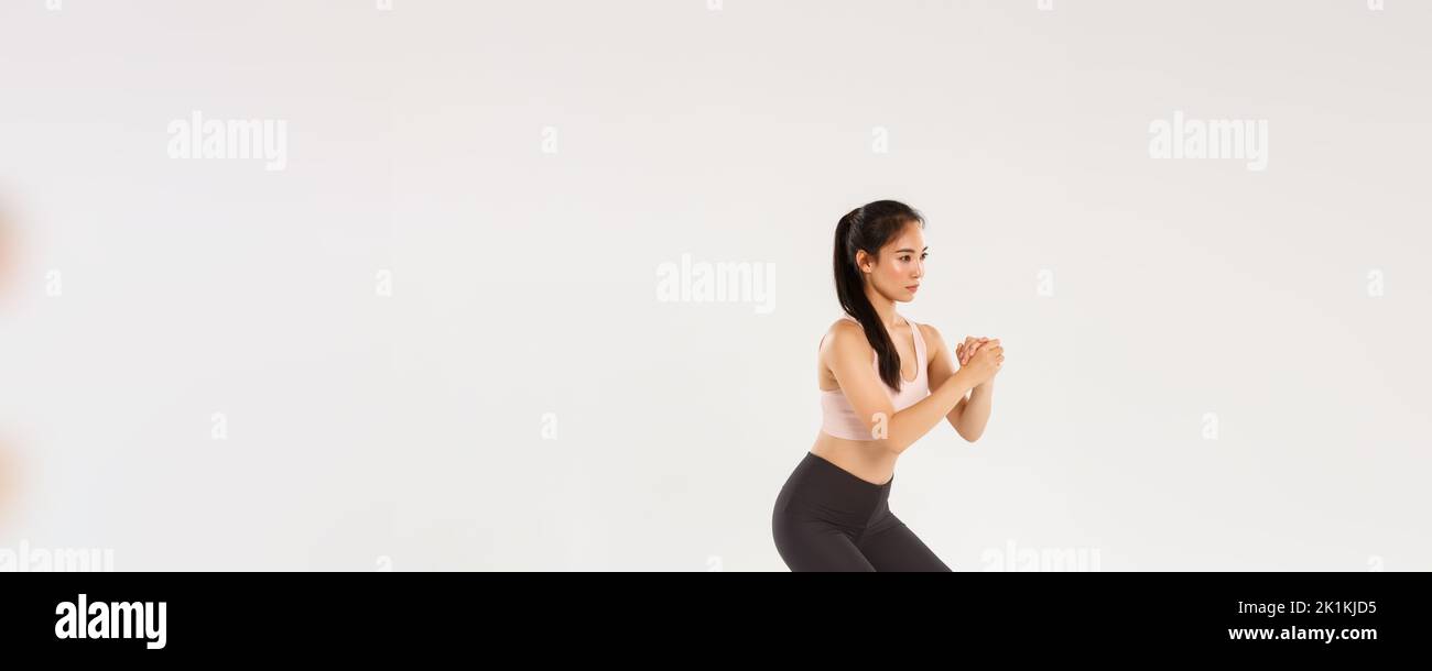 Full length side view of focused slim asian girl doing fitness training ...