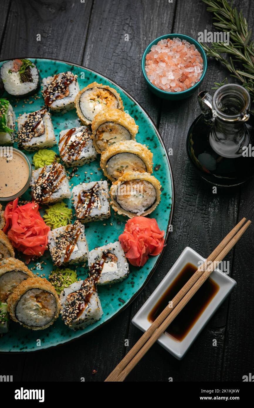A vertical of different kinds of sushi rolls on a green plate with ...