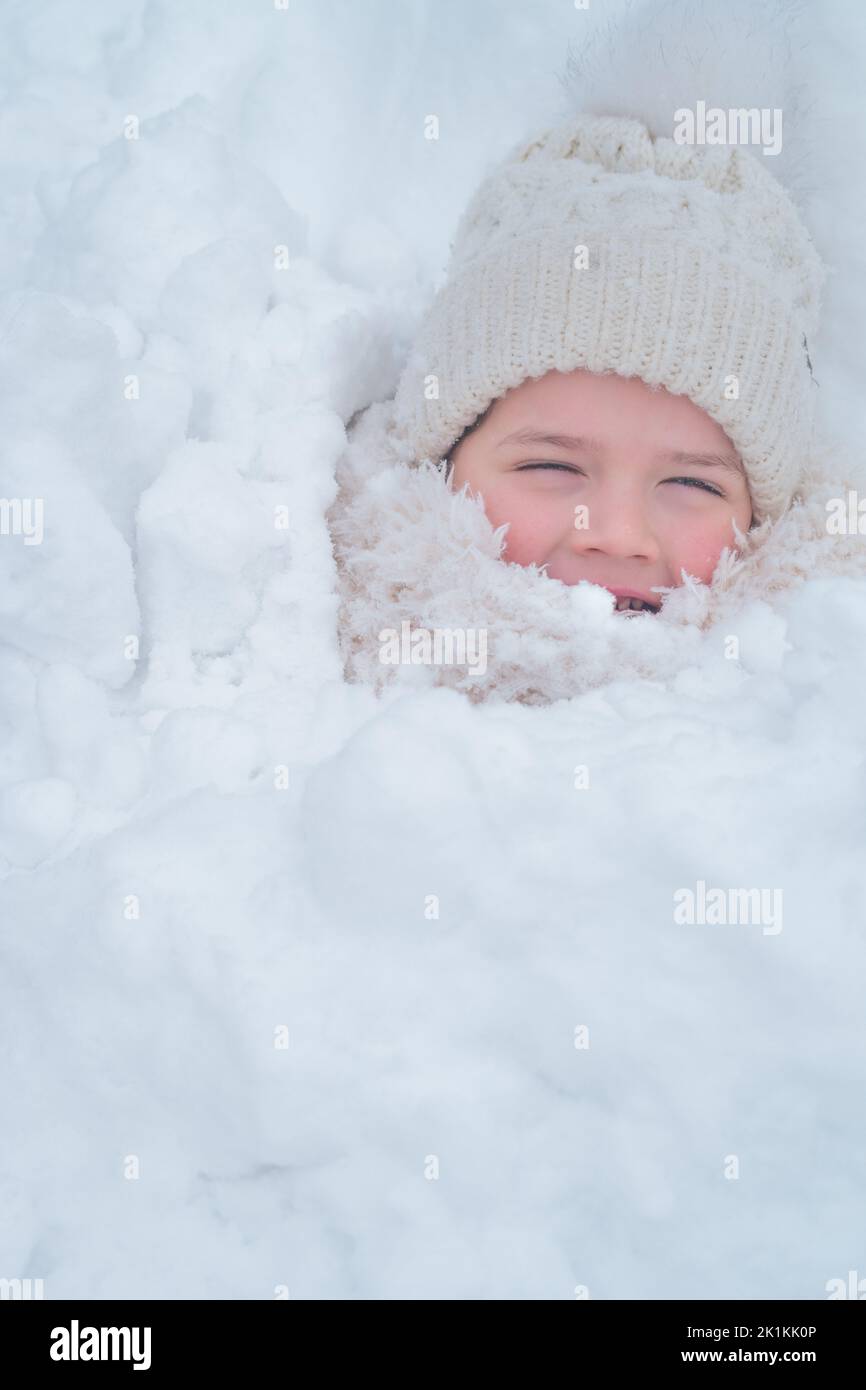 Child, 6 years old boy laughing and hiding in the snow. All body ...