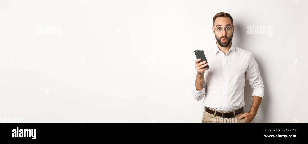 Surprised handsome man reading interesting info online, holding ...