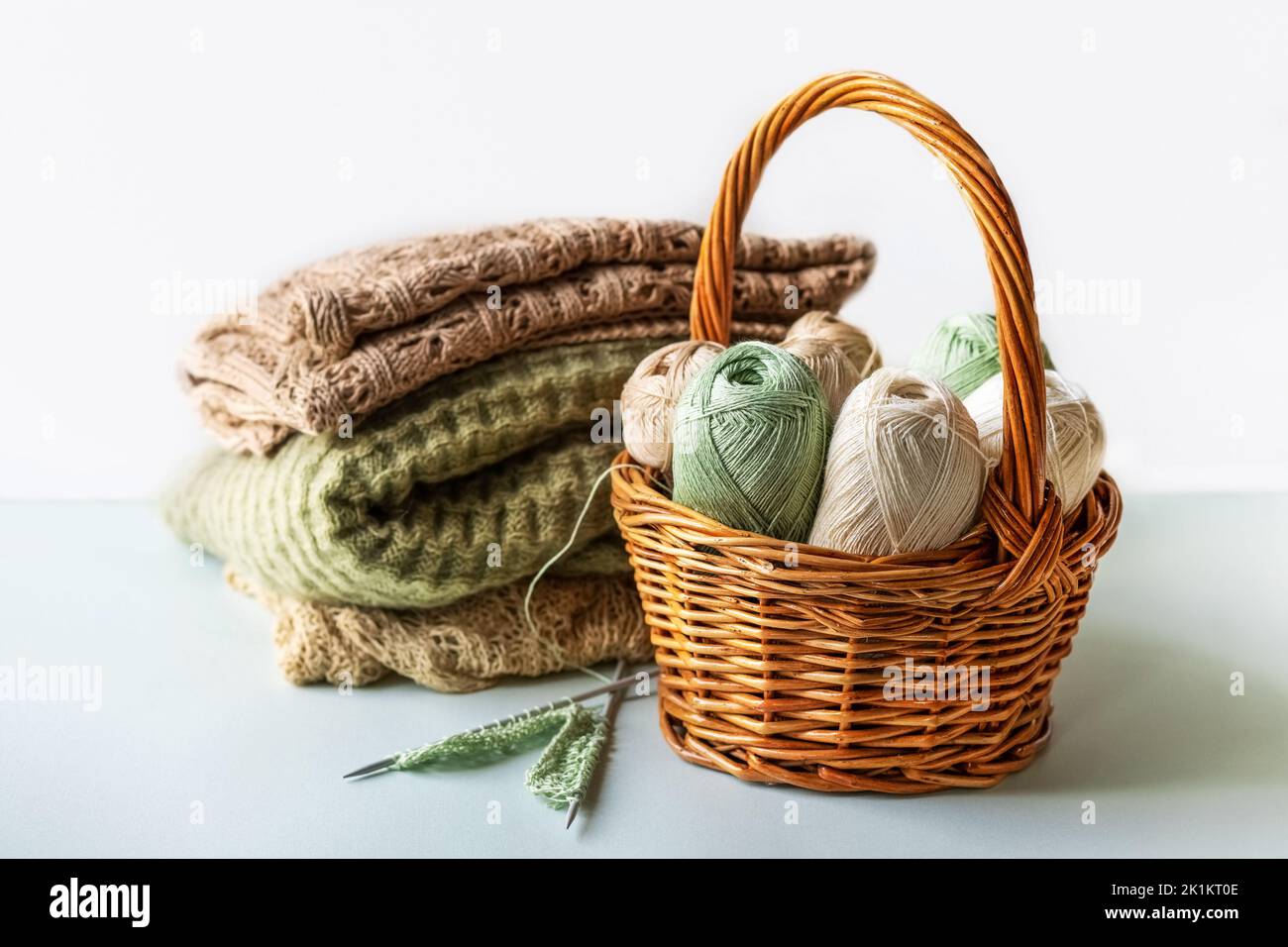 Green and brown yarn threads in a basket for knitting warm clothes with ...