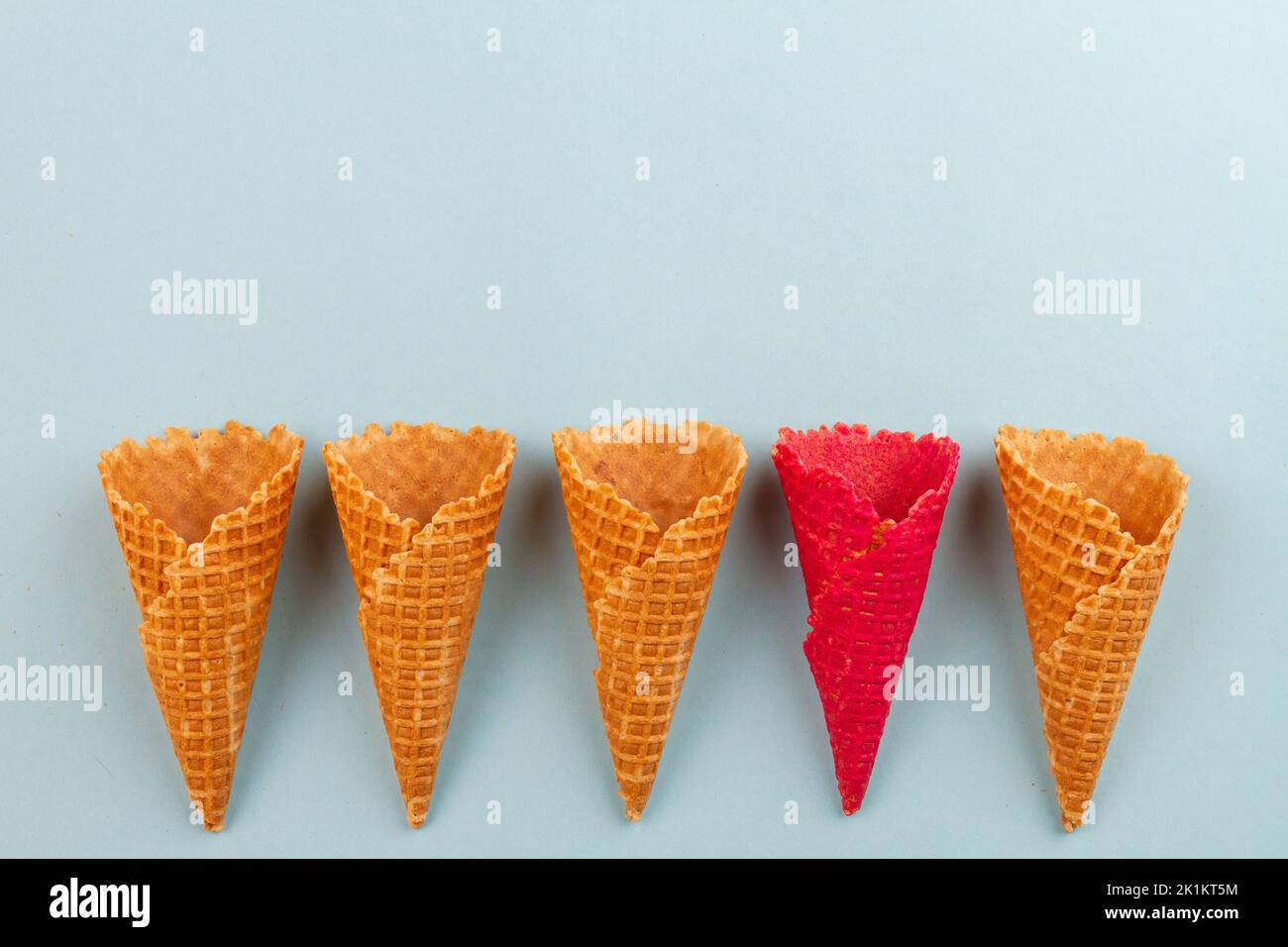 Red ice cream cone waffle amoung ordinary ones. Blue pastel background ...