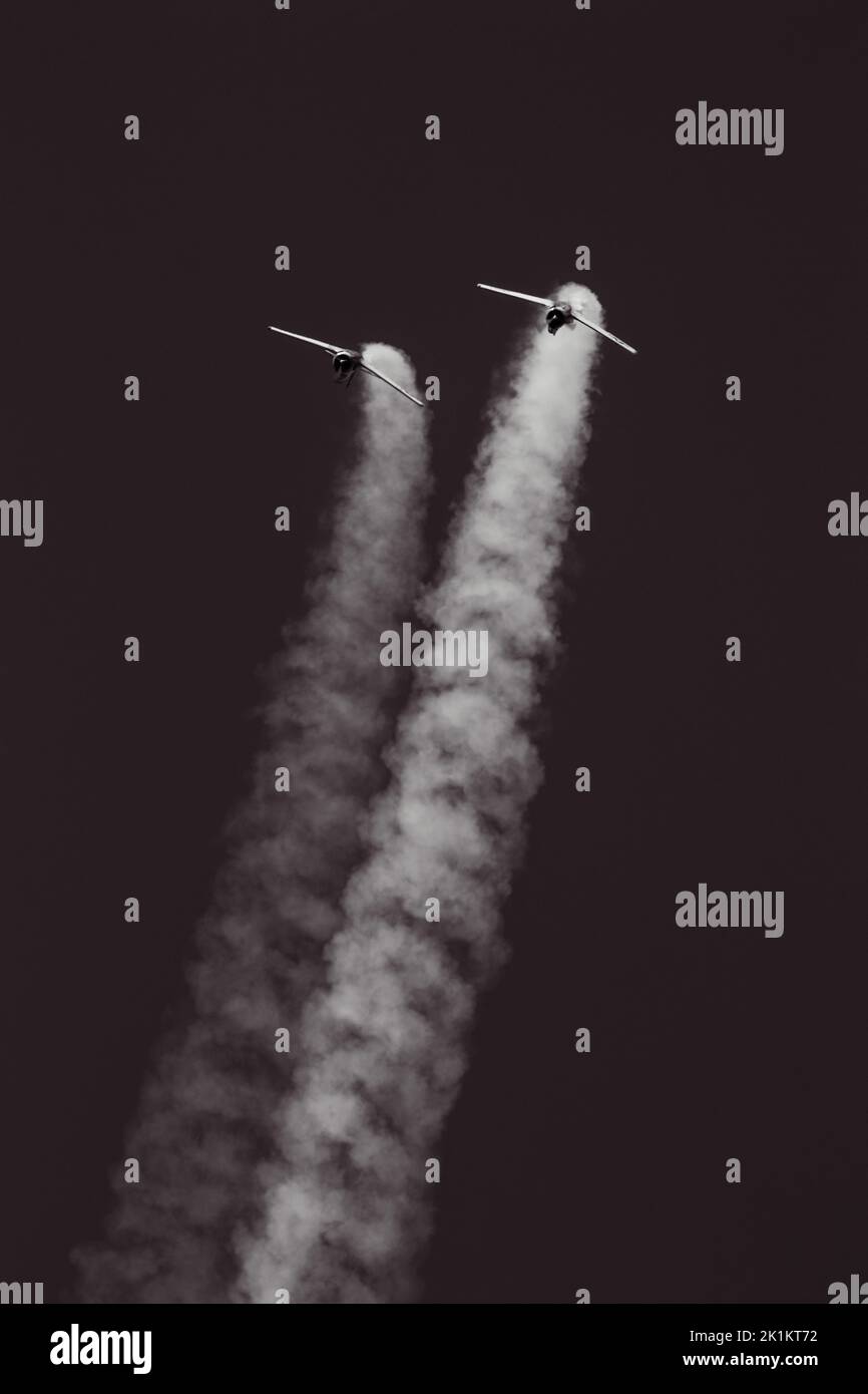 A vertical of two airplanes flying in the sky with smoke Stock Photo ...