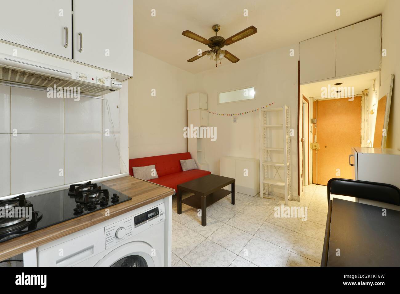 Open plan apartment with shabby furnishings with a kitchenette, a ...