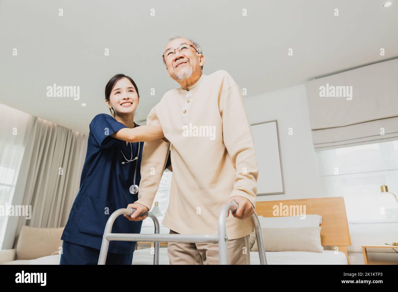 Smiling nurse woman helping senior Asian man to walk around the nursing ...