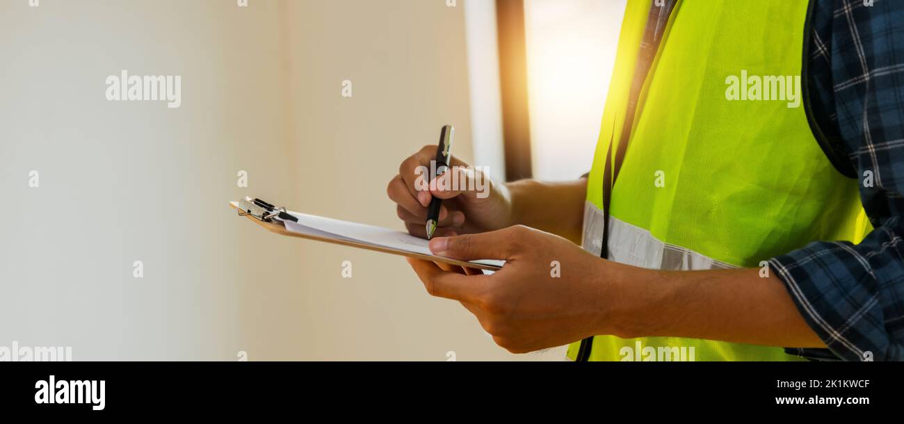 close up hands of inspector wear safety vest and checking list into ...