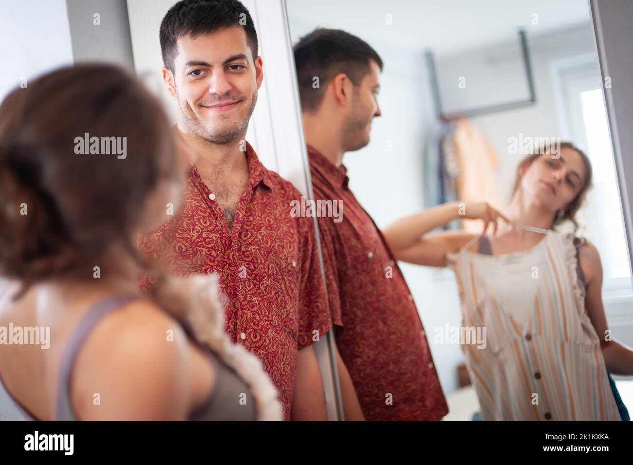 A charming young couple trying on clothes and having fun standing ...