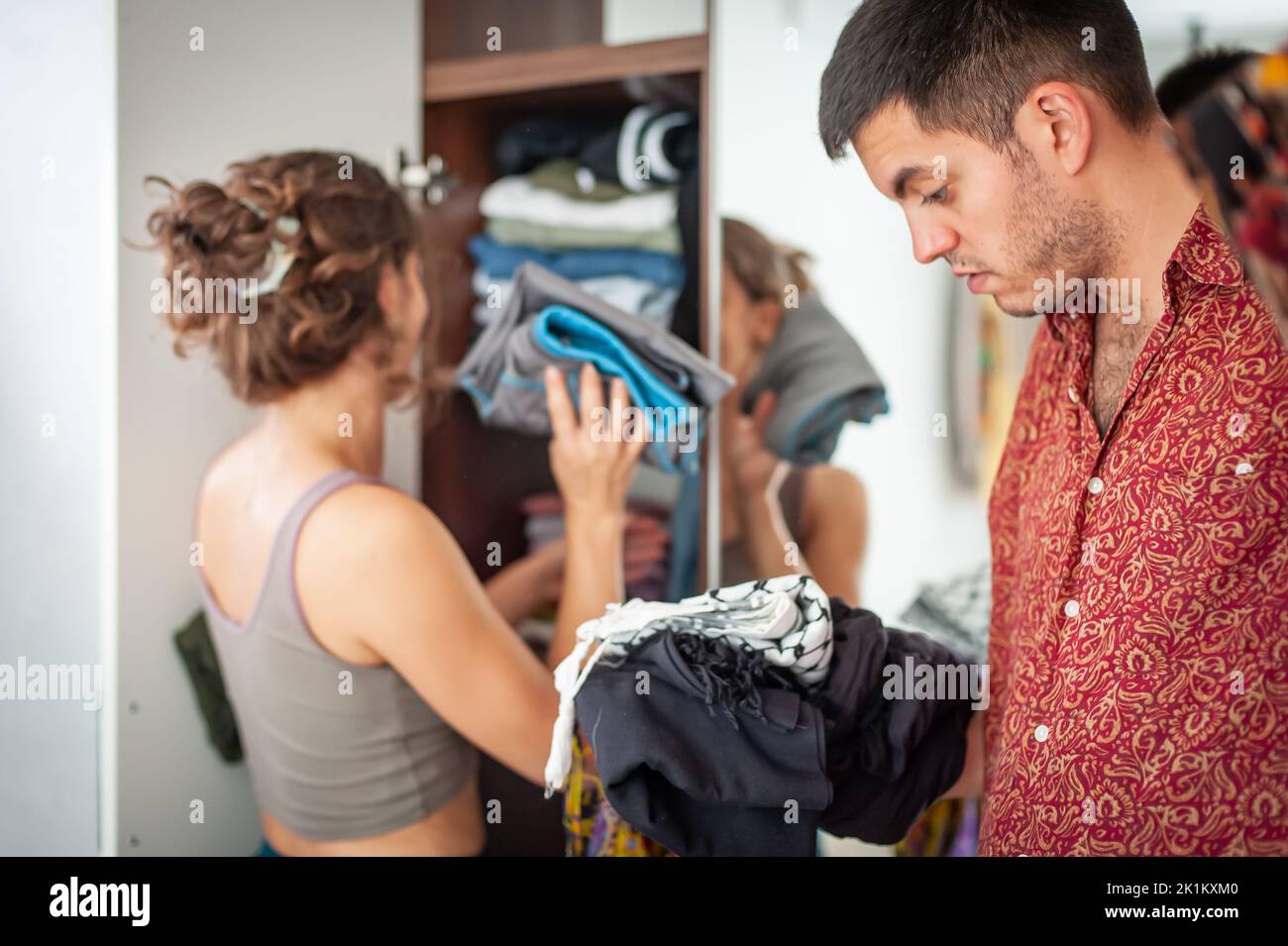 A charming young couple trying on clothes and having fun standing ...