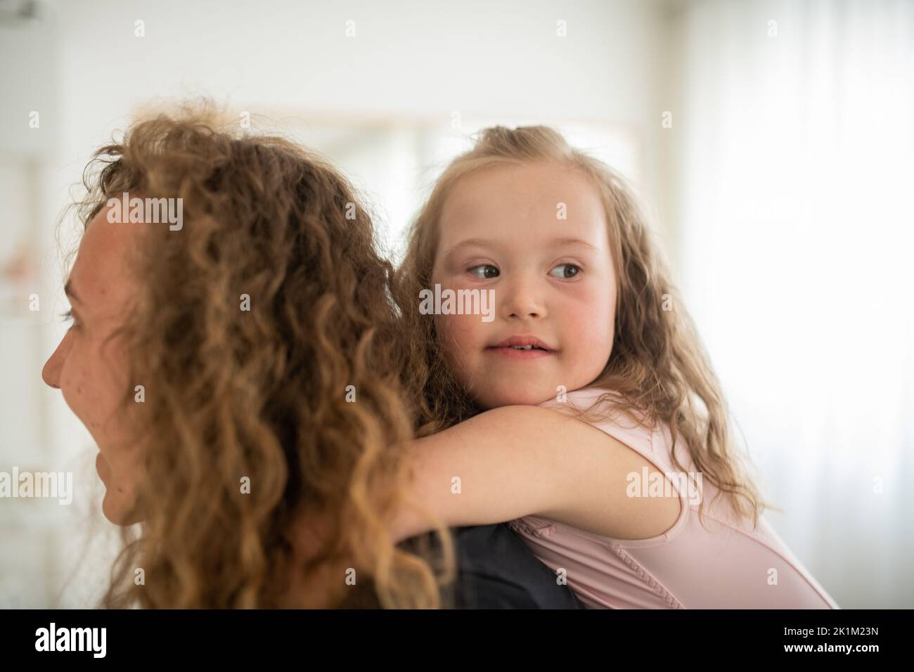 Young happy mother holding her daughter with down syndome piggyback ...