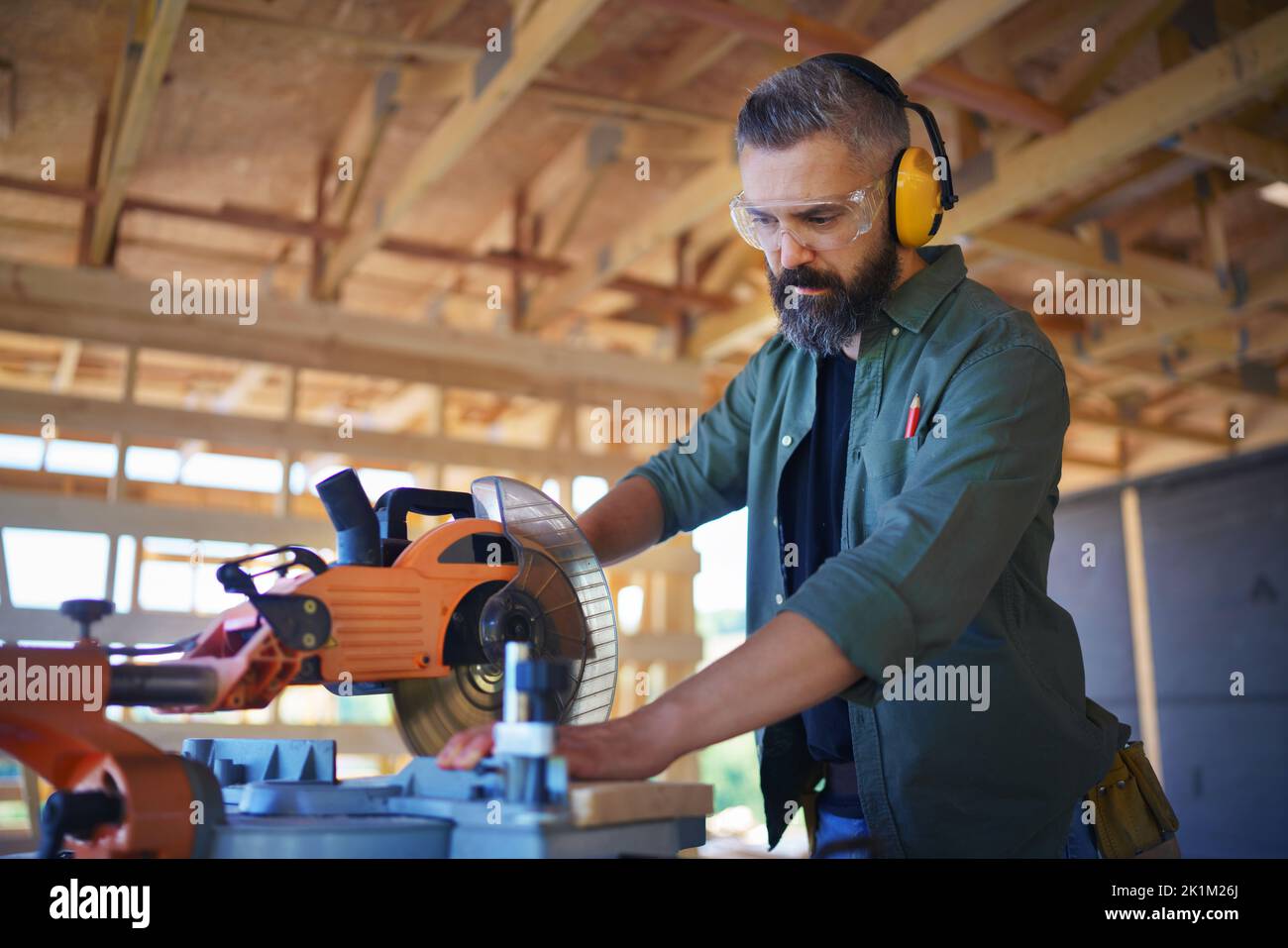 Construction worker working with eletric saw inside wooden construction ...