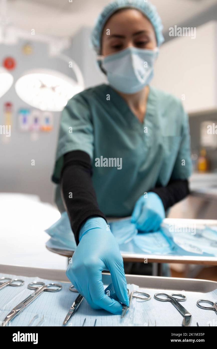Female nurse preparing surgical scissors on tray in operating room ...