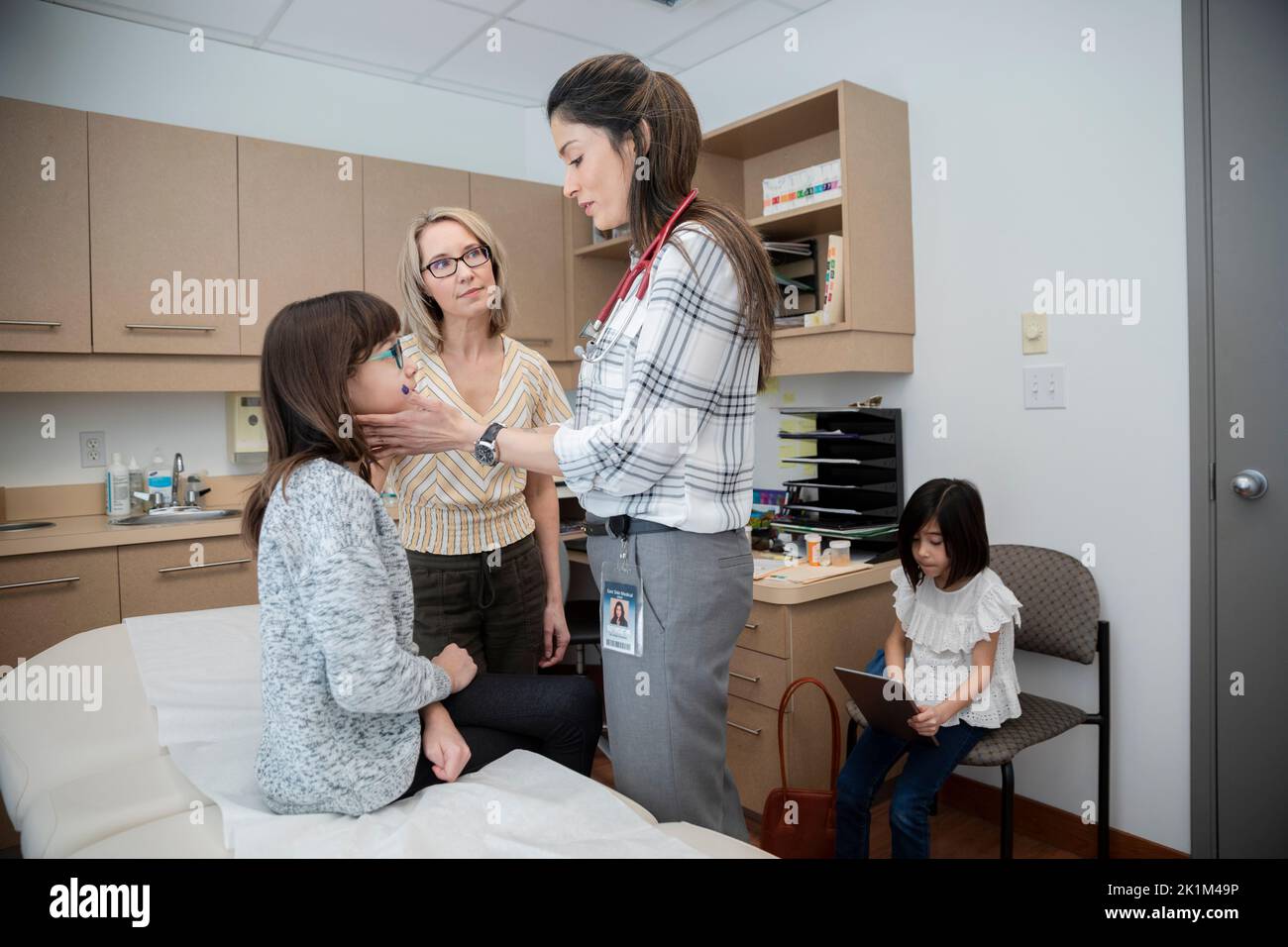 Female pediatrician examining girl patient in clinic exam room Stock ...