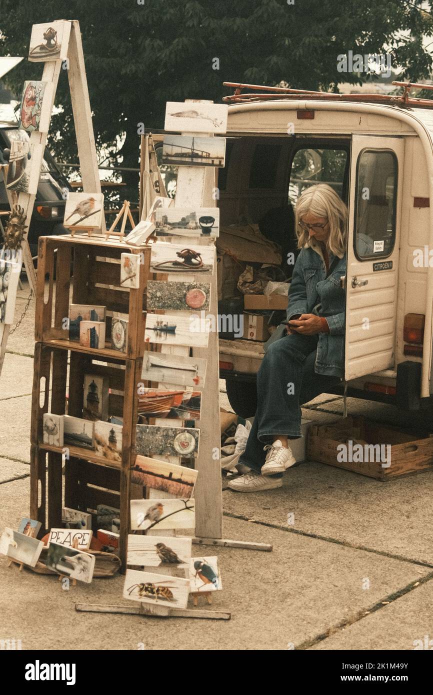 The vertical view of a woman sitting on the edge of a vintage van ...