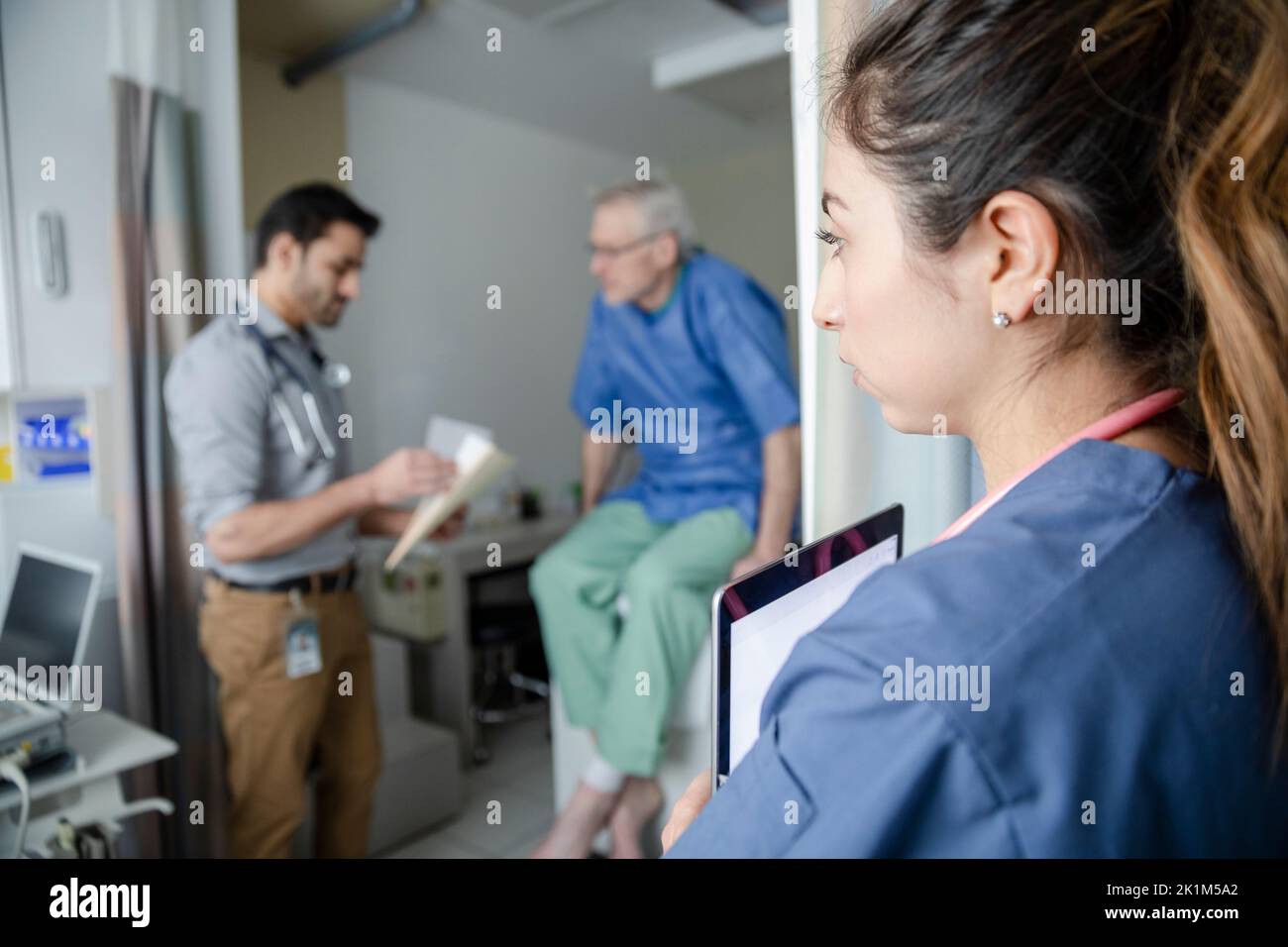 Female nurse watching doctor prepare senior patient for surgery Stock ...