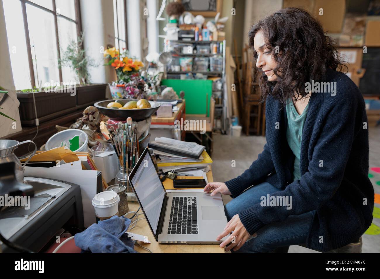 Artist sitting in studio using laptop Stock Photo - Alamy