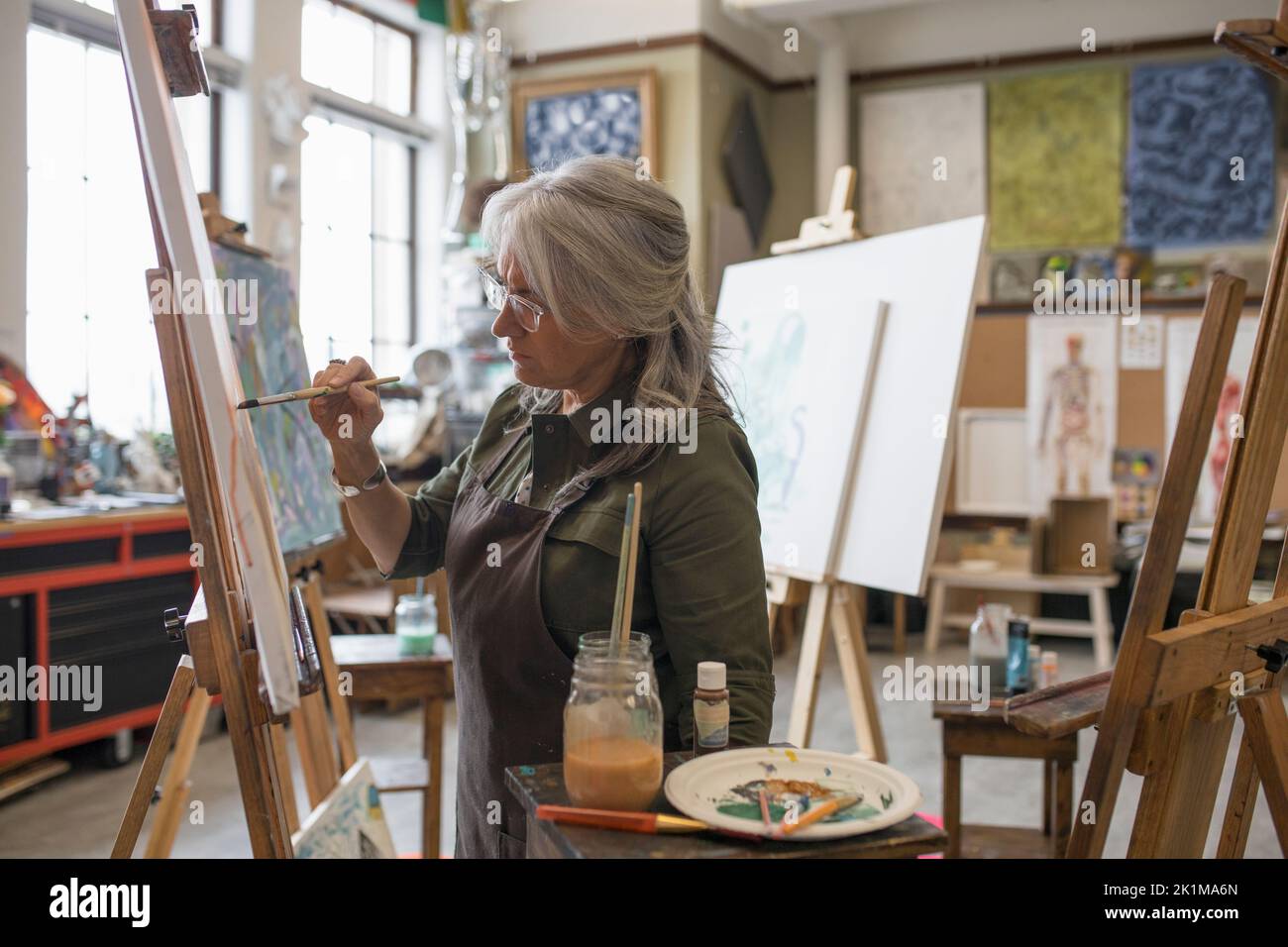 Mature woman painting on easel in studio Stock Photo - Alamy