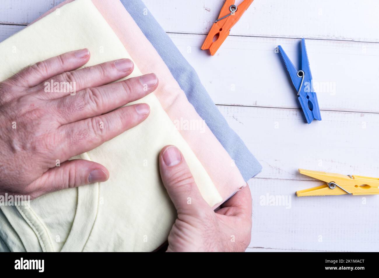 A hand folding the clothes and a tweezers hanger on the table Stock ...