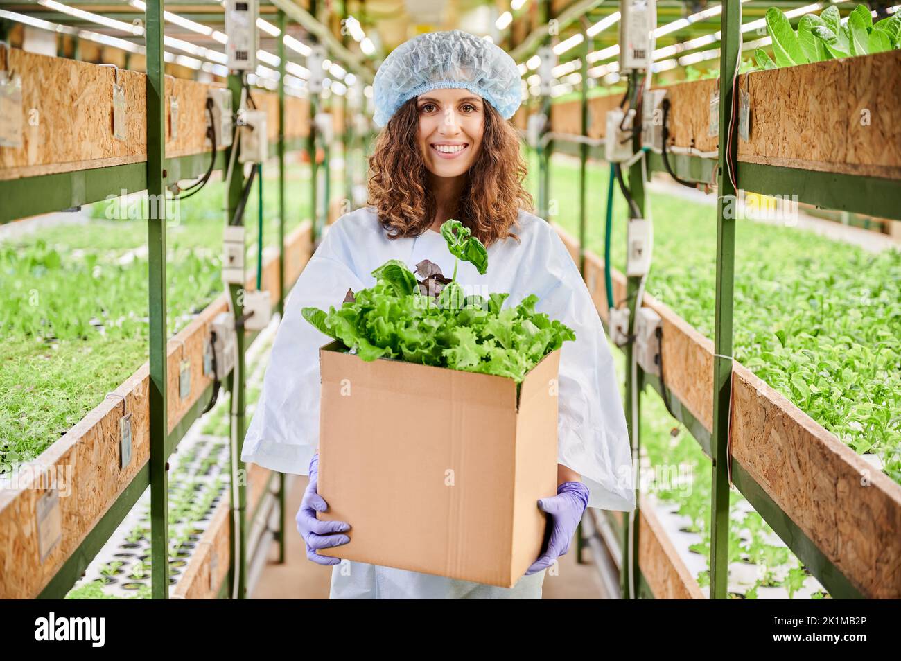 Joyful female gardener looking at camera and smiling while holding ...
