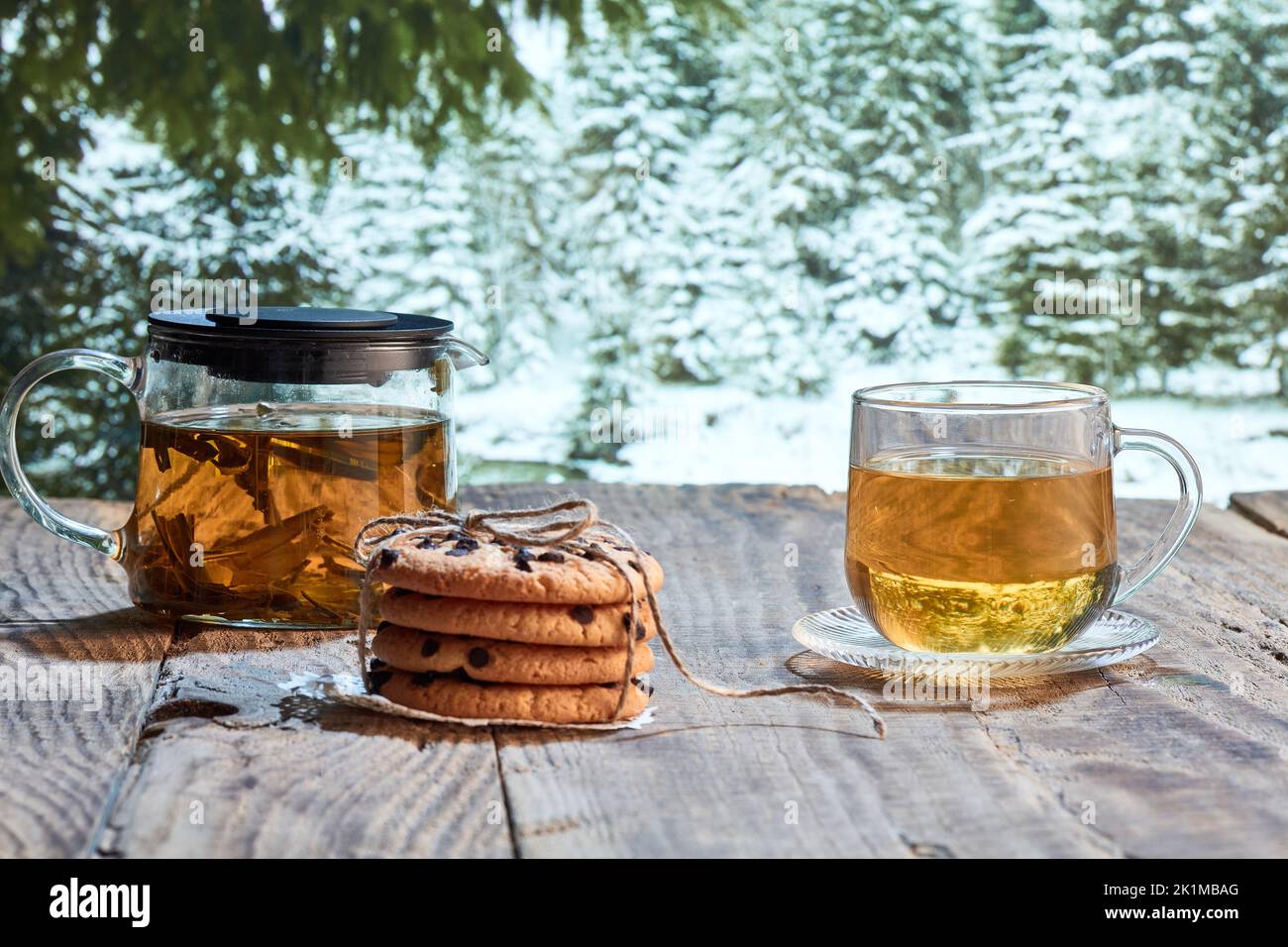 Winter still life. Glass pot with herbal tea, cakes, biscuits on wooden ...