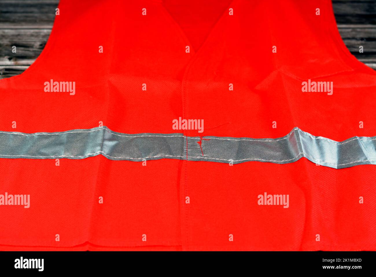 Red reflective safety vest with reflective stripes isolated on wooden ...