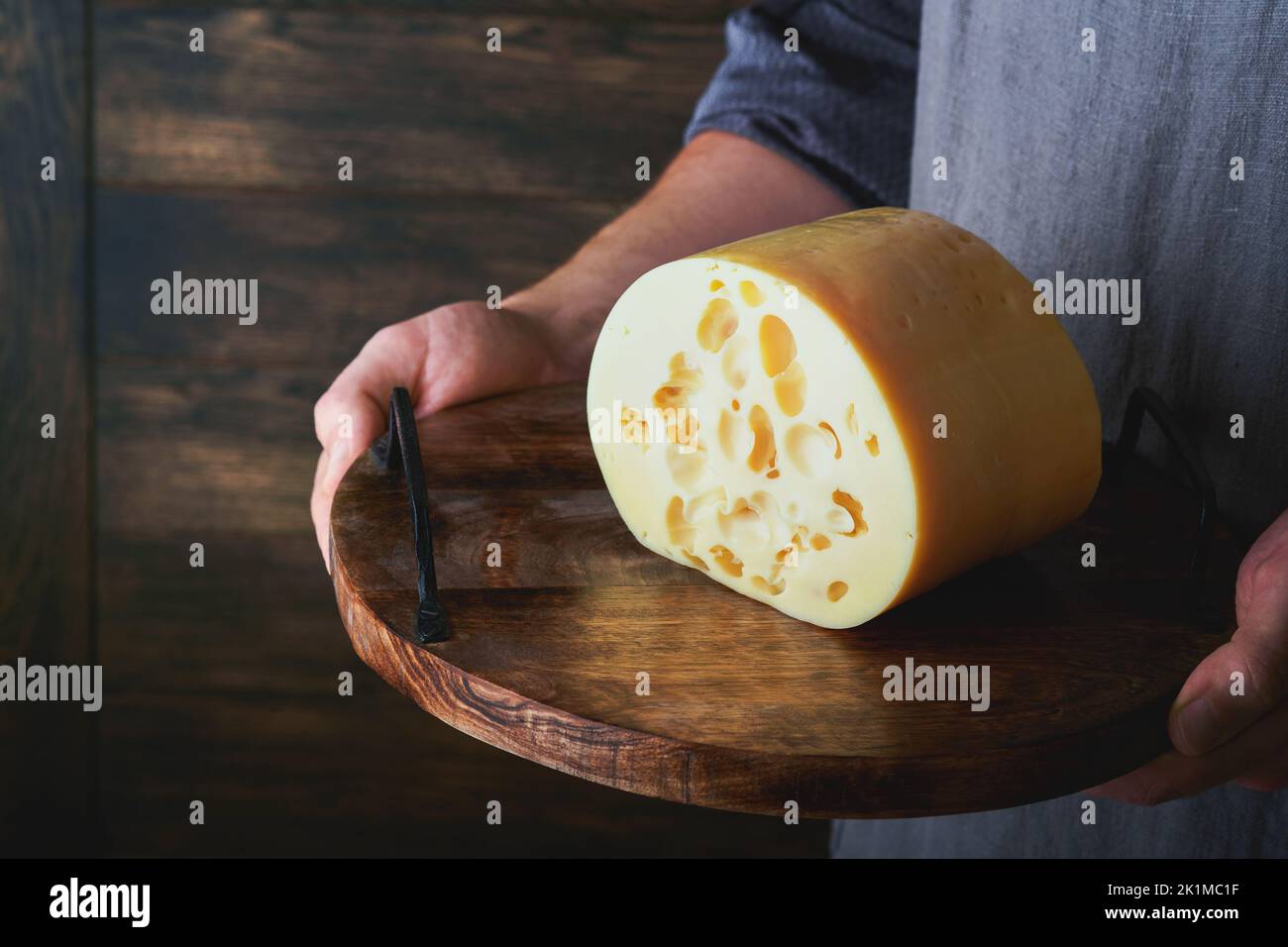 Hands of man hold two big slices of cheese maasdam against background ...