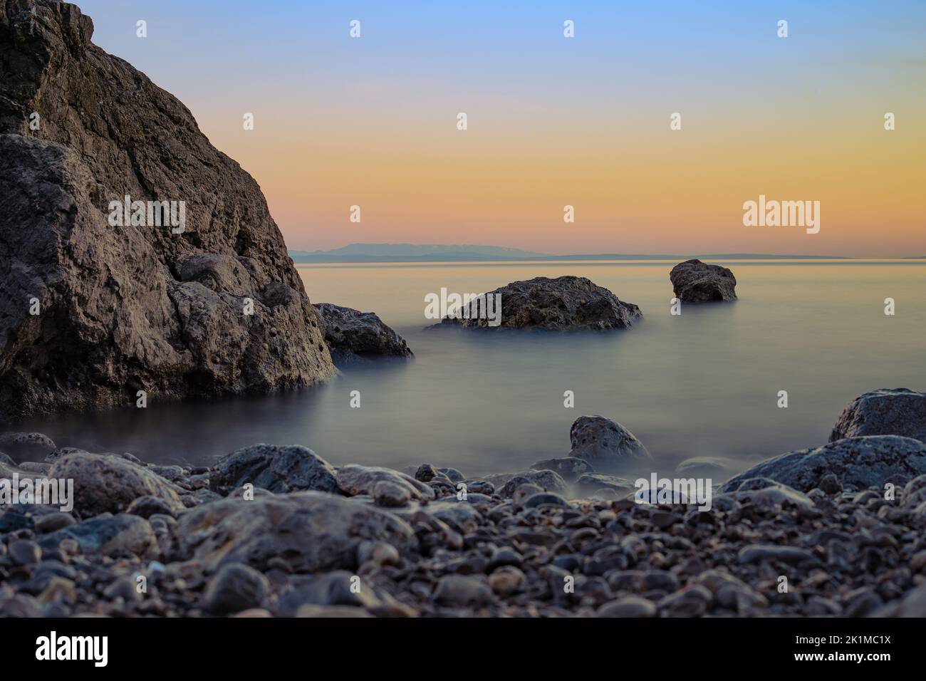 Calm rocky seascape during golden hour Stock Photo - Alamy