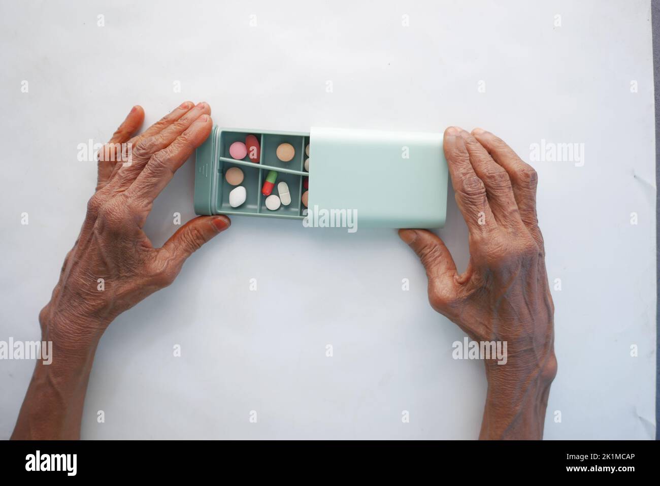 senior women taking medical pills from a pill box on white background ...