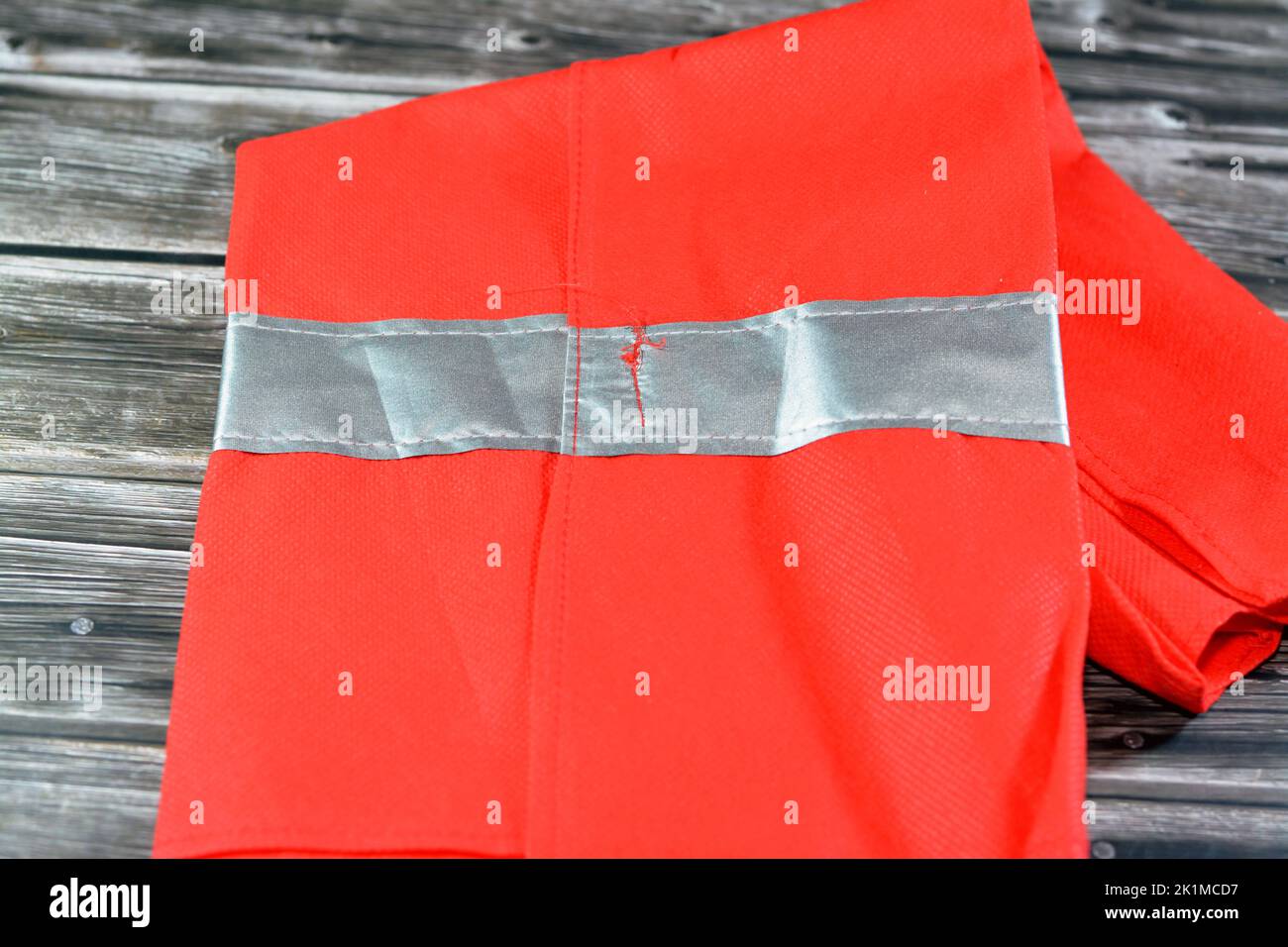 Red reflective safety vest with reflective stripes isolated on wooden ...