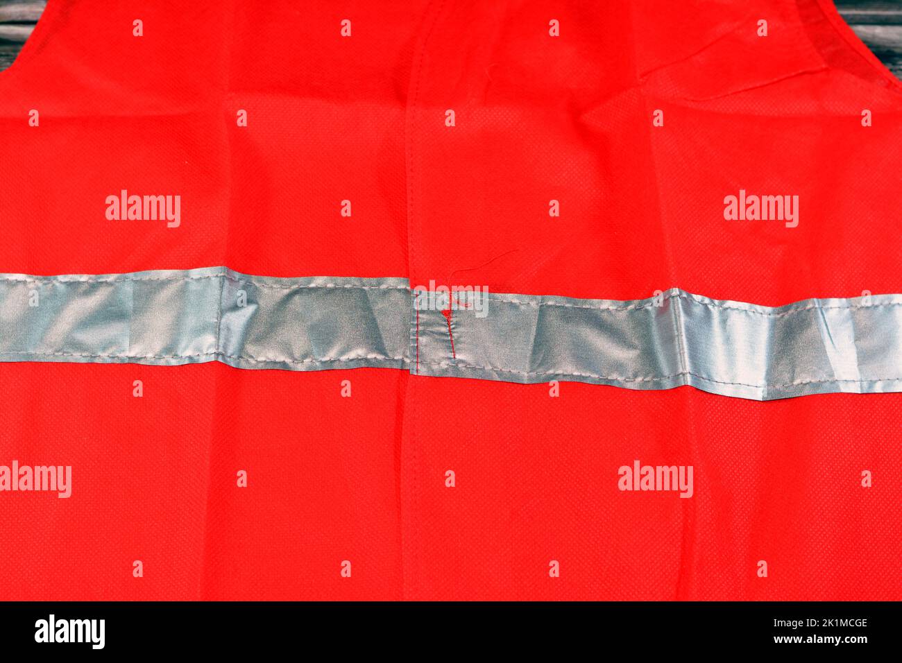 Red reflective safety vest with reflective stripes isolated on wooden ...