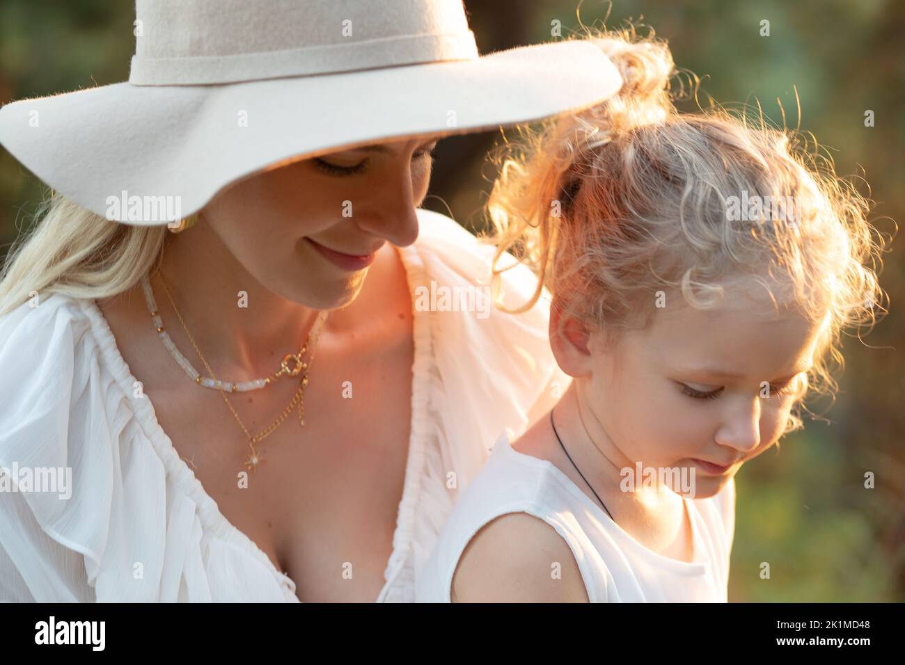 Portrait of loving family wearing white dresses, sitting near trees in ...