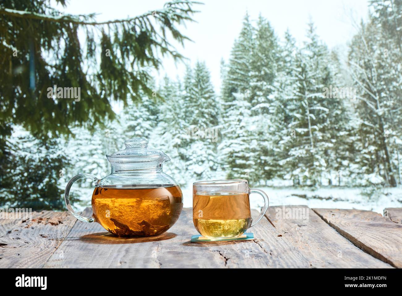 Winter still life. Glass pot with herbal tea on wooden table over ...