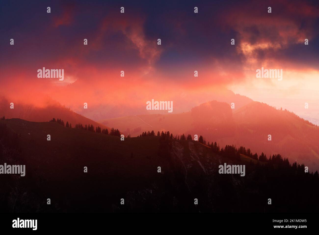 dramatic sunset with clouds and the sun in the Alpine foothills of ...