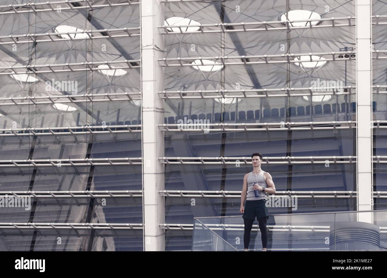 Athlete handsome man relaxing and drinking sport drink, modern stadium ...