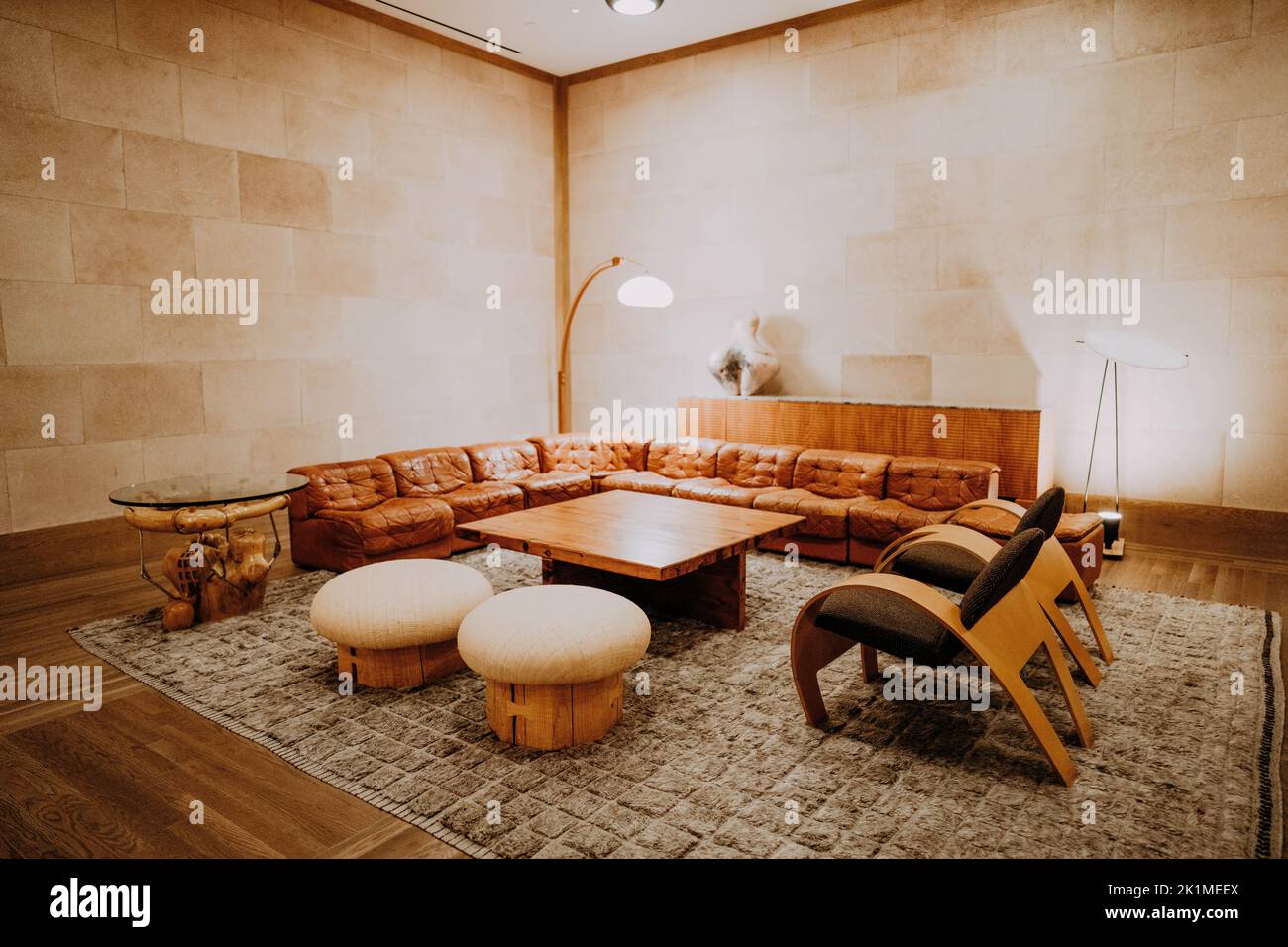A beautiful hall interior with brown leather sofa and wooden armchairs ...