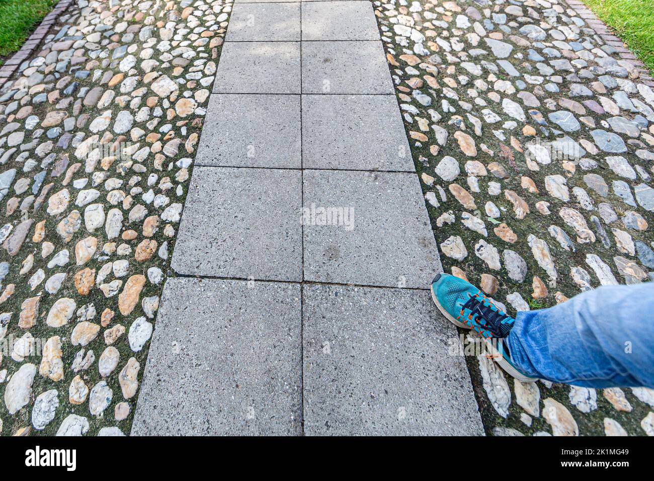 Pathway made of stones with huge gray bricks in the center, male leg in ...