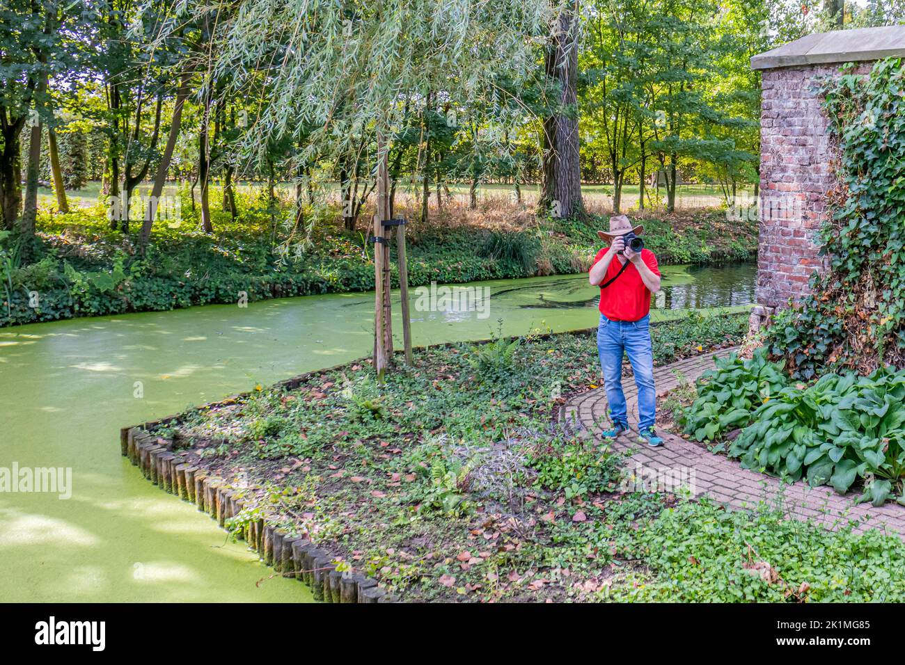 Scene of a male photographer in action taking photo standing on a path ...
