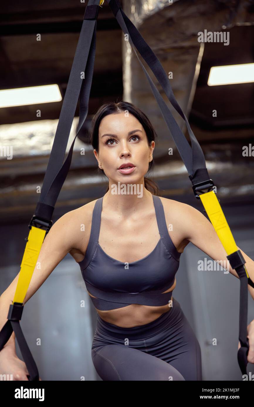 Young fit woman exercises with tapes at the gym. Vertical view Stock ...