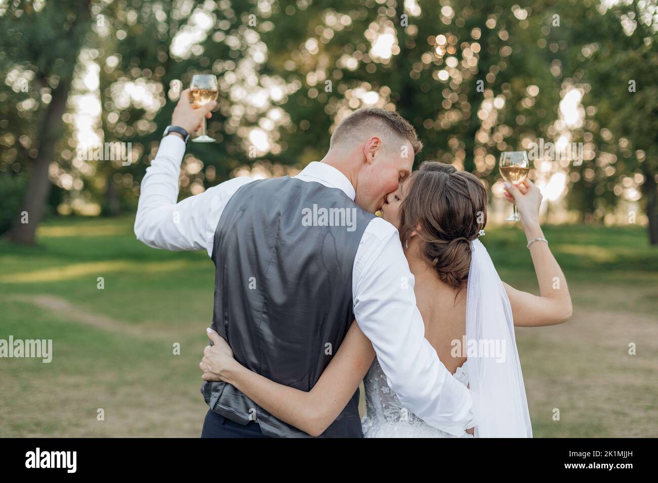 Young man groom kissing hugging young beauteous woman bride, raising ...