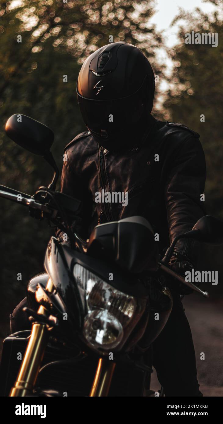 A vertical closeup shot of a rider sitting on a motorcycle wearing a ...