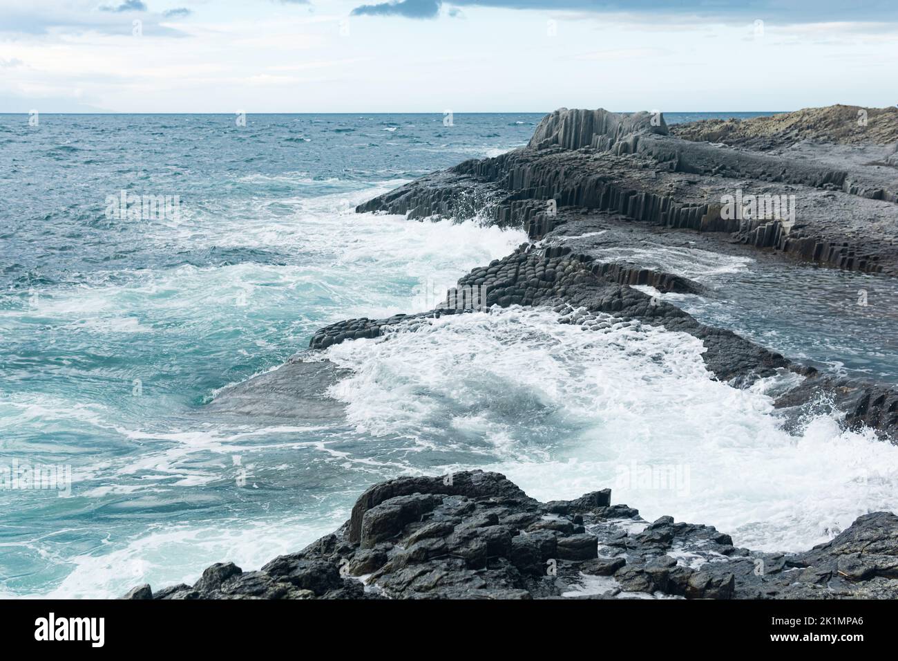 rocky seashore formed by columnar basalt against the stormy sea ...