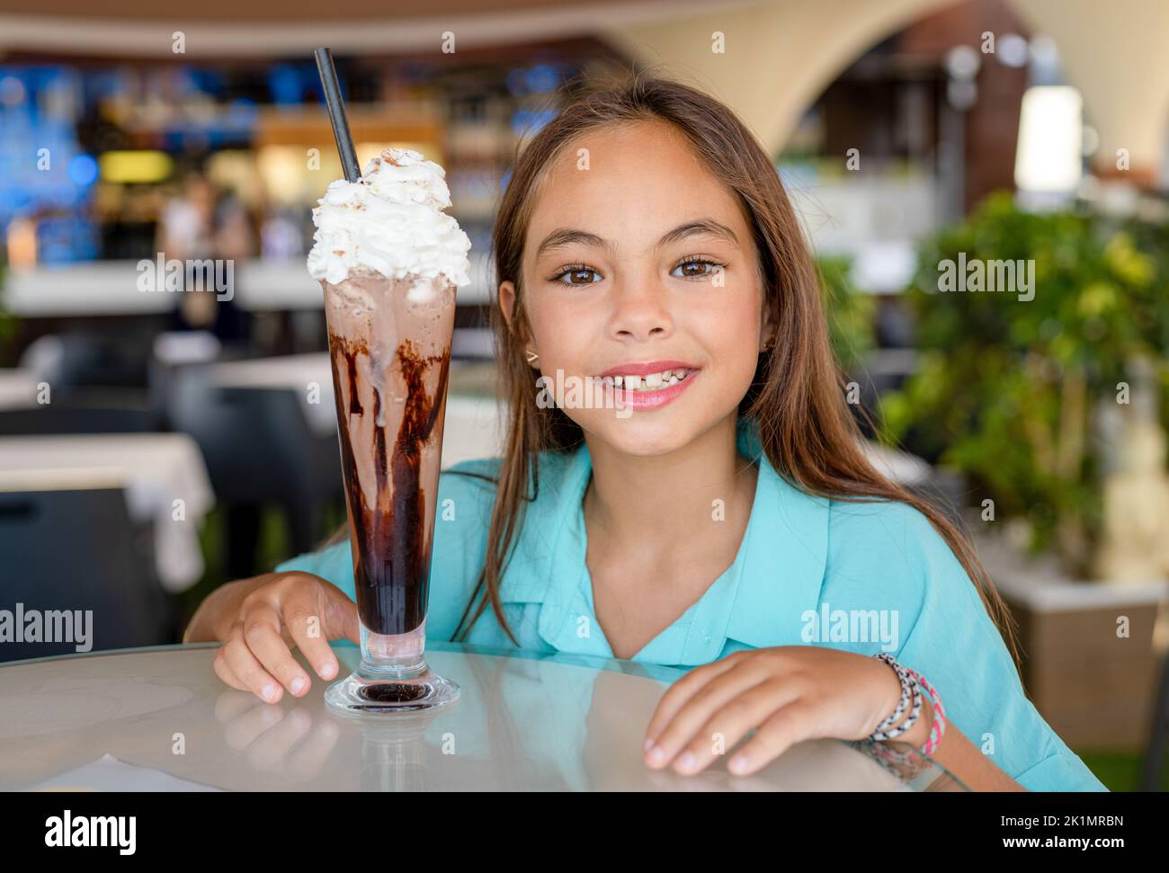 Beautiful child kid girl eating a chocolate shake in a restaurant. Cold ...