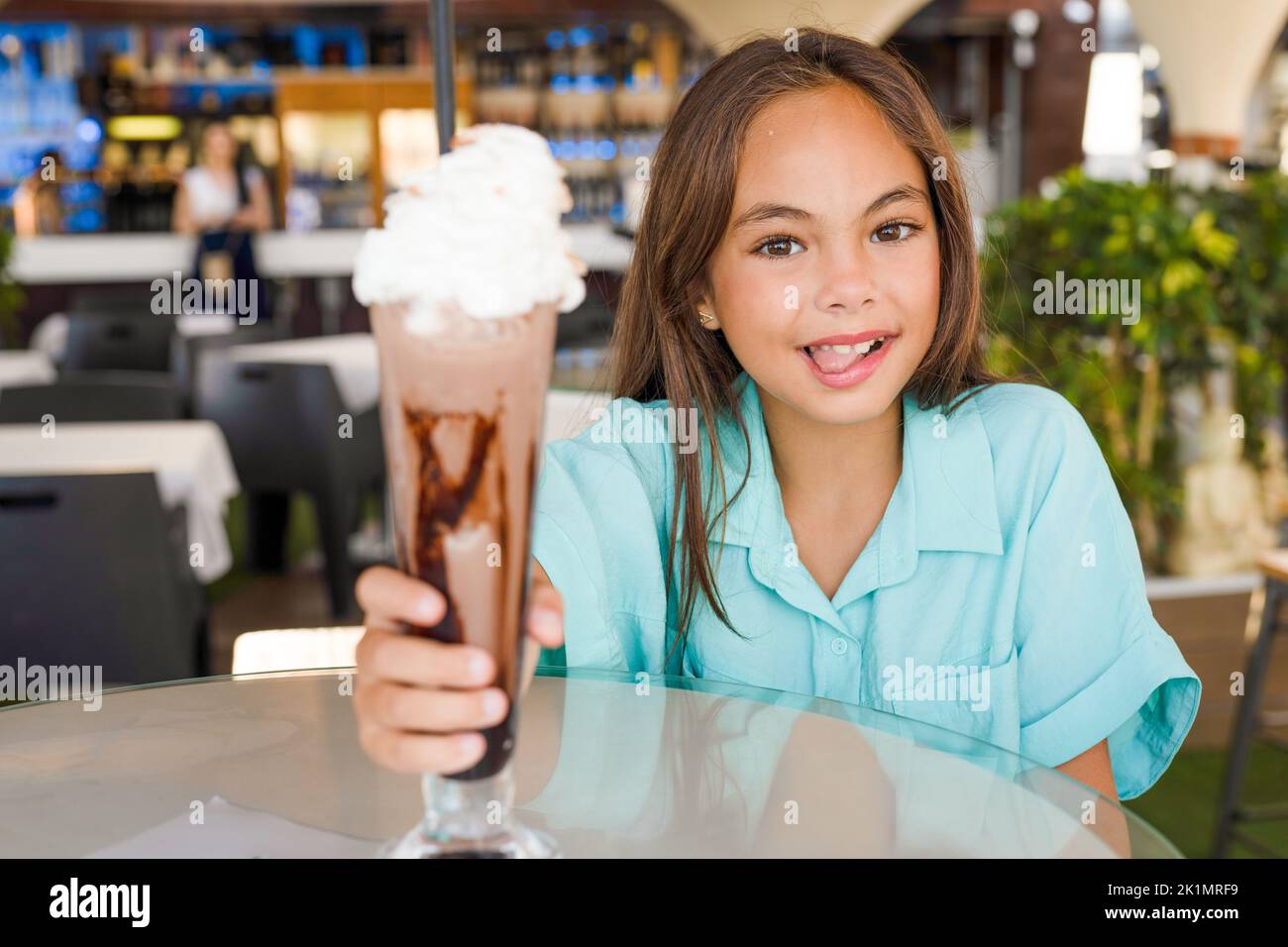 Beautiful child kid girl eating a chocolate shake in a restaurant. Cold ...