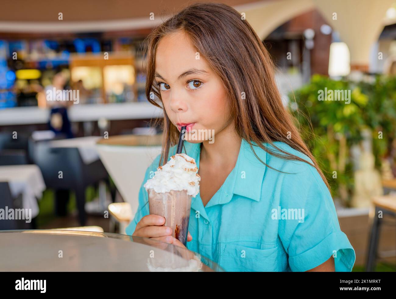 Beautiful child kid girl eating a chocolate shake in a restaurant. Cold ...