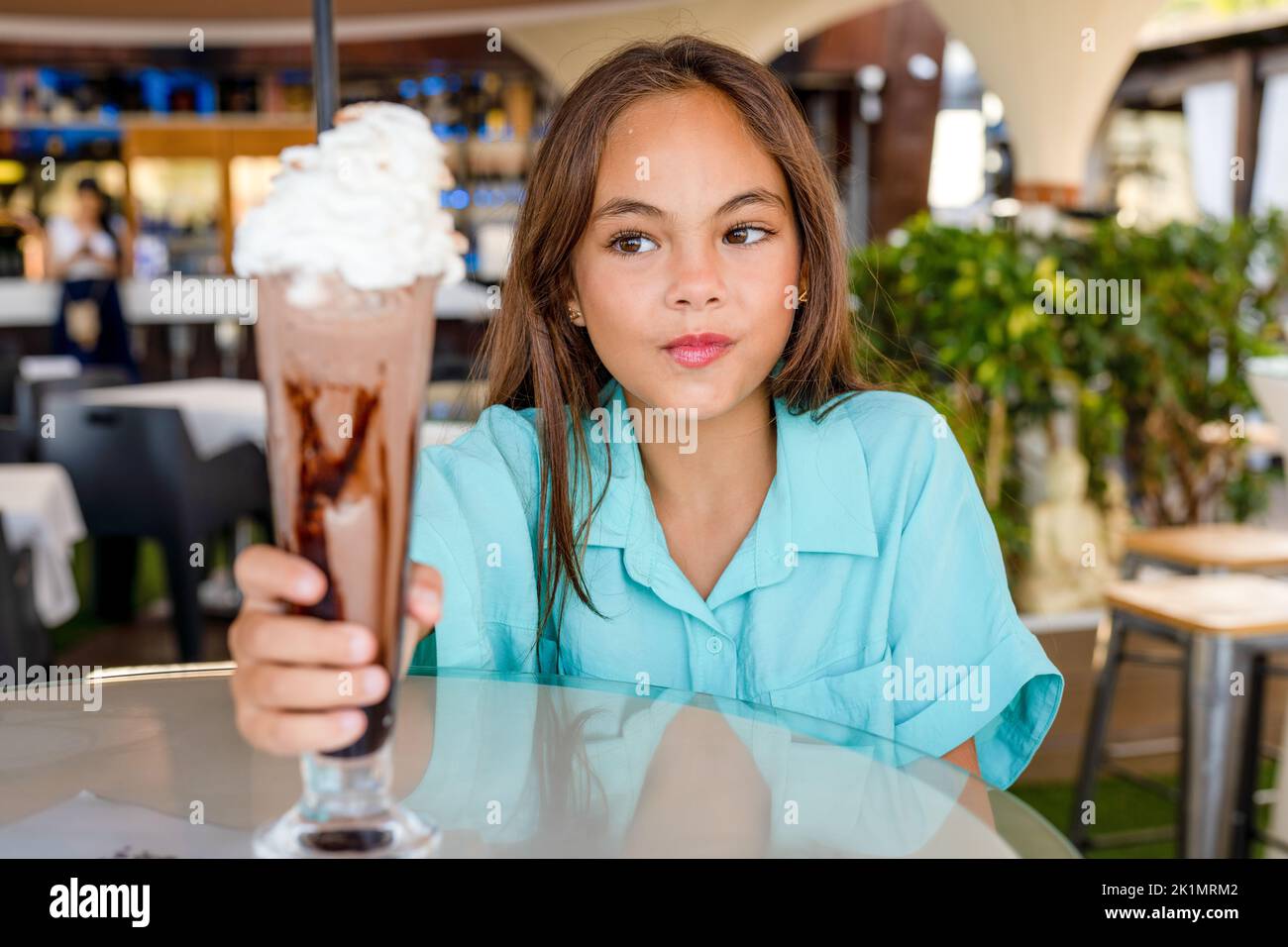 Beautiful child kid girl eating a chocolate shake in a restaurant. Cold ...