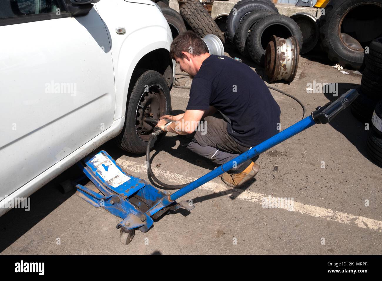 Young man worker changing a tyre on the wheel of a car in Llandovery ...
