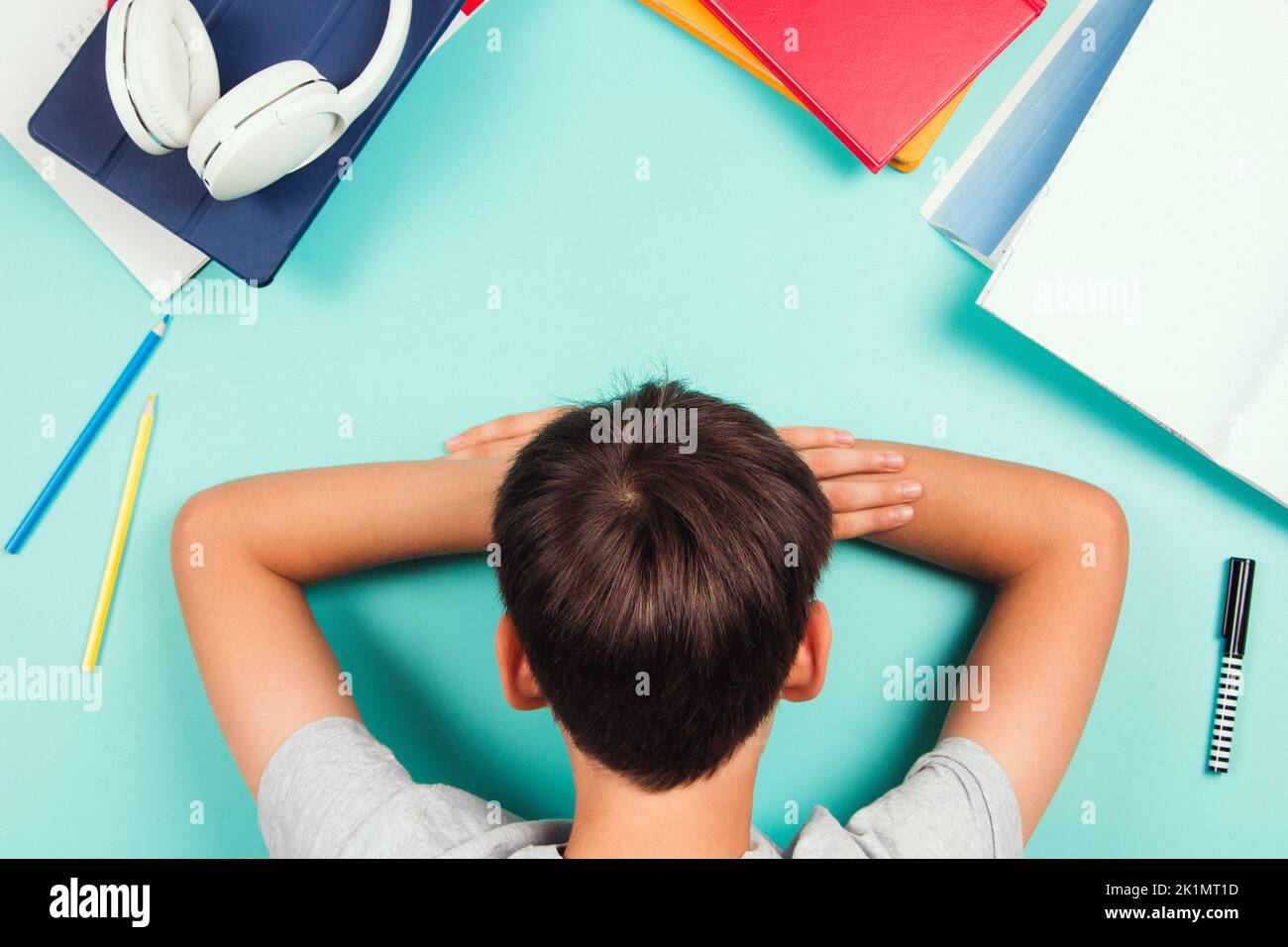 Sad tired frustrated teenage boy lies on the table with many books ...