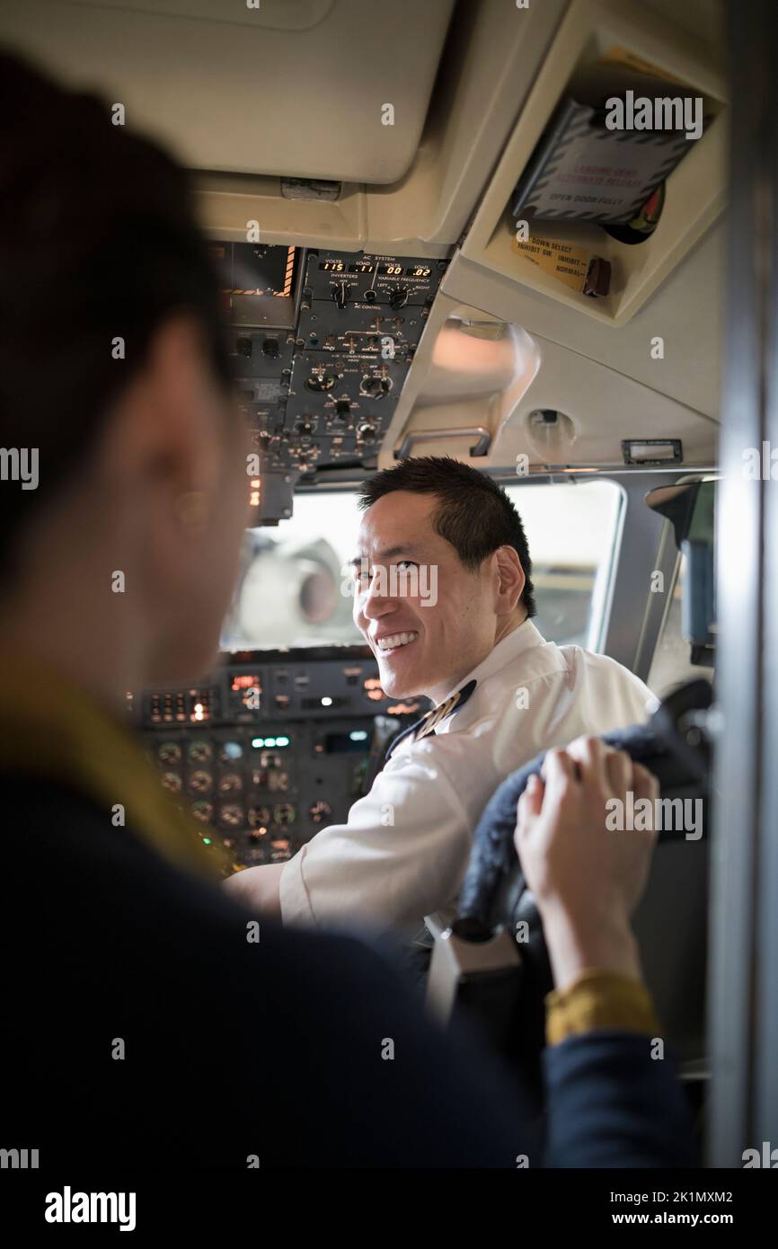 Smiling pilot talking with flight attendant in airplane cockpit Stock ...