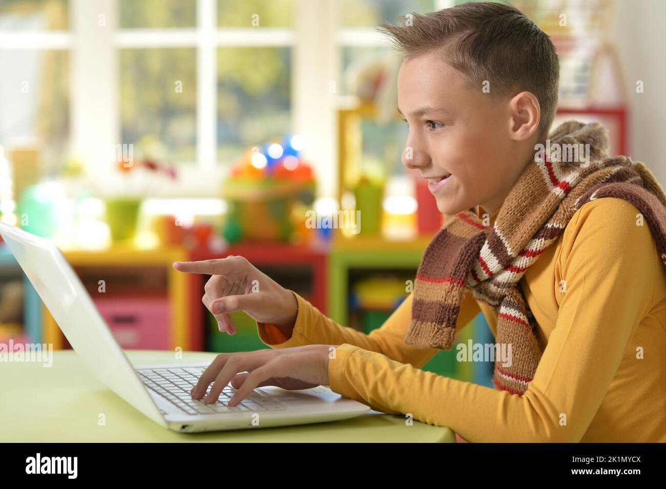 Cute boy with laptop at the table Stock Photo - Alamy